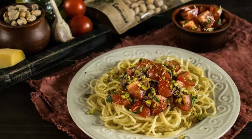 Tambahkan saus di spageti yang sudah jadi, taburi dengan pistachio dan oleskan ke meja