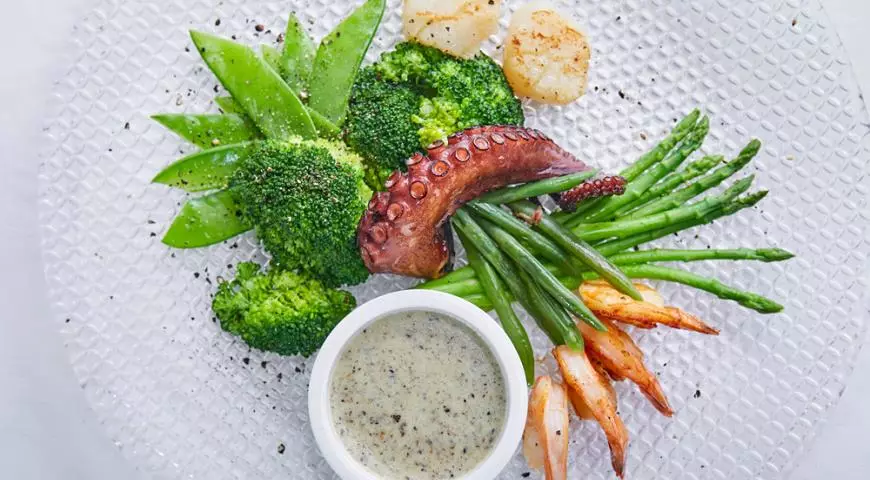 Cooking a warm seafood salad with green vegetables and truffle sauce