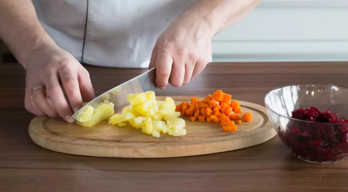 कप मध्ये एक फर कोट अंतर्गत, grater वर sandpaper beets, आणि carrots आणि बटाटे चौकोनी तुकडे मध्ये कट