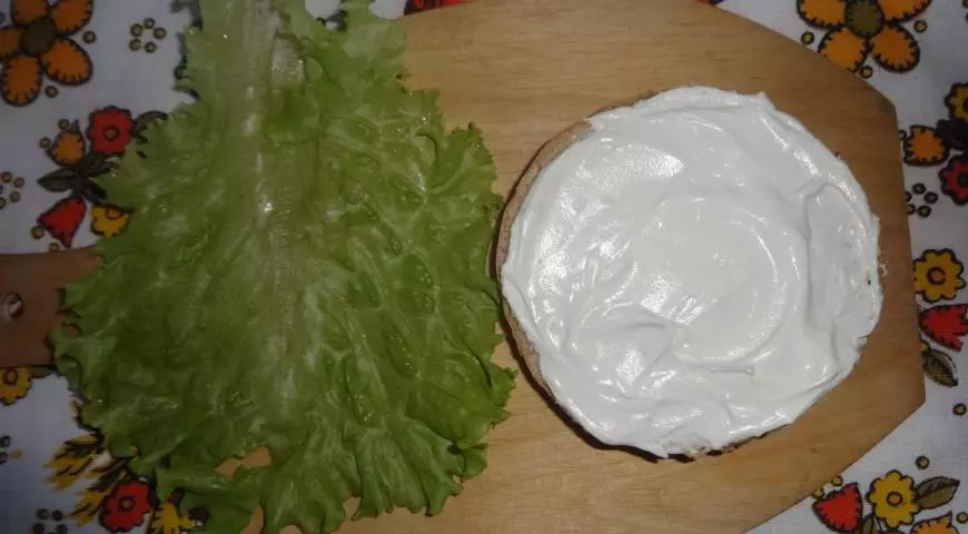 Cortar un bollo para la hamburguesa y lubricar el fondo de la crema agria.