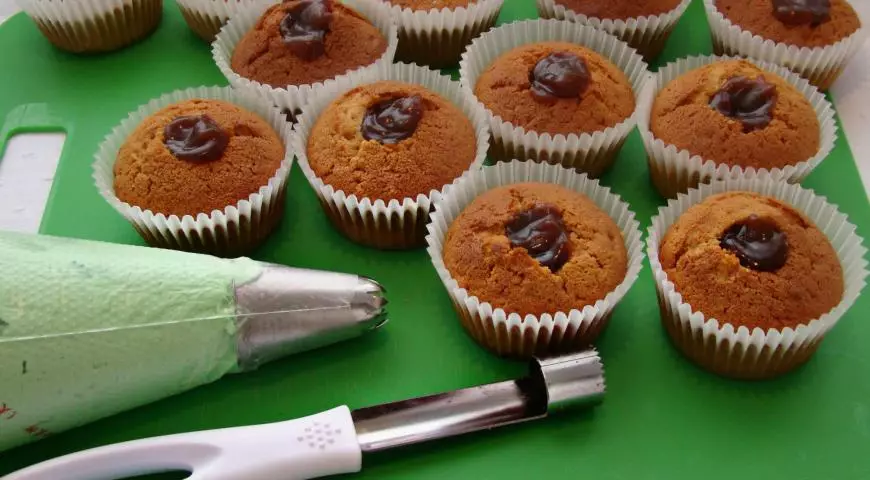 Cupcakes principais enchem caramelo, transferências de creme em seringa