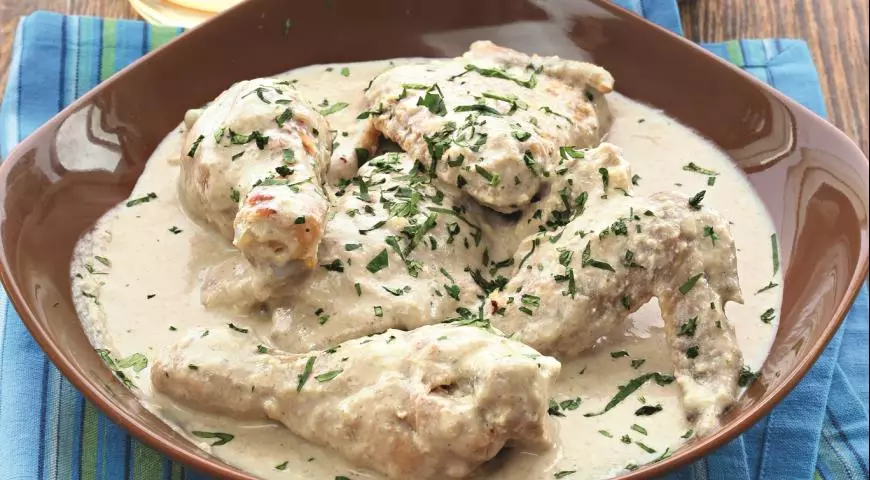Grind parsley leaves. Spread pieces of chicken over deep plates and pour the creamy sauce. Sprinkle with parsley and serve.