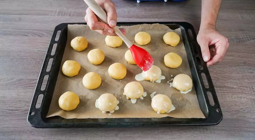 Les galetes amb un embús de pinya a l'interior, estableixen boles preparades en una safata de forn, lubricar amb llet condensada