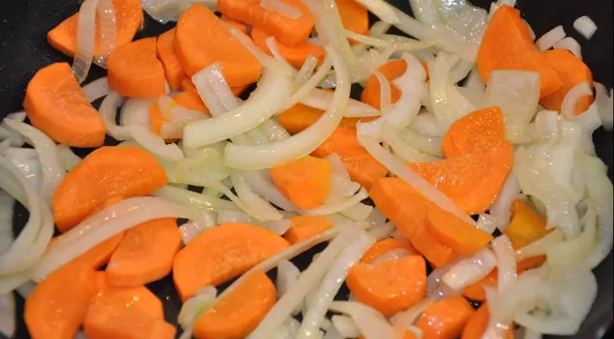 Freír cebollas con zanahorias en una sartén.