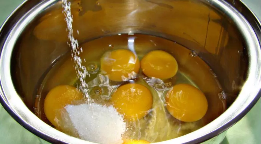 Para la galleta genovés, los huevos se dividen en una cacerola, agregue azúcar, ponga un baño de agua.