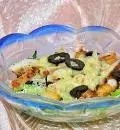 Meletakkan salad caesar dengan mentimun dan zaitun di atas piring