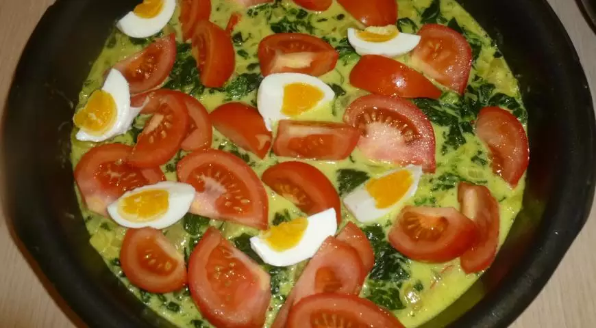 In the form pour the mixture with spinach, lay out the sliced ​​eggs and tomatoes