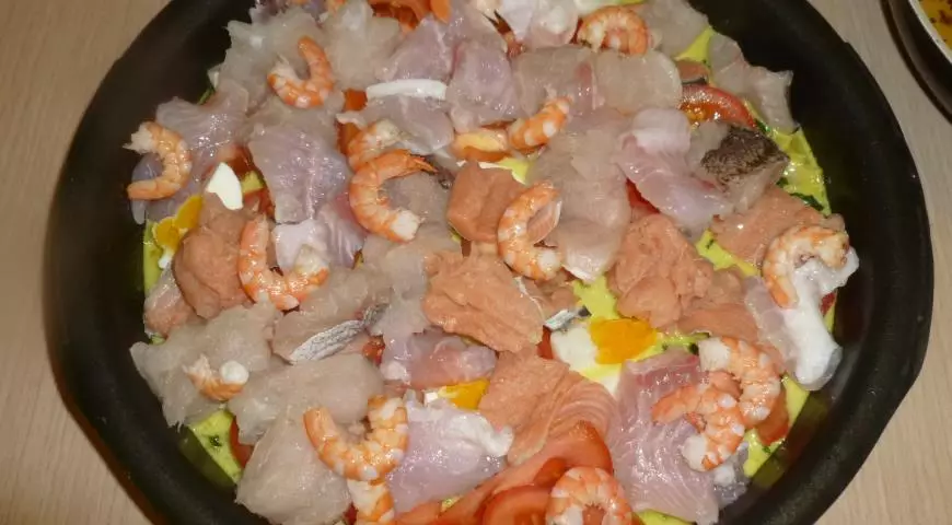 Fish for casserole cut by pieces and lay out with shrimps in the form