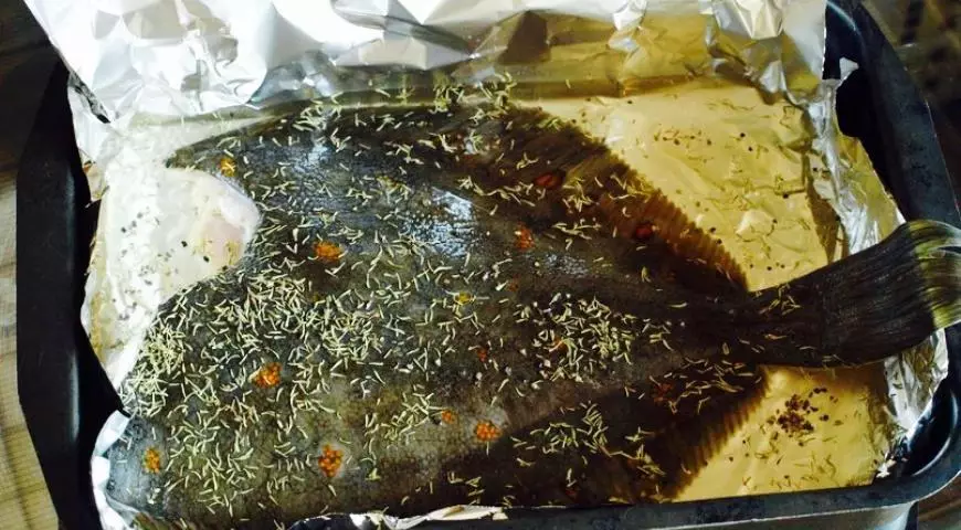 Sett fisk på et bakeplate med folie, legg til krydder, hell på hvitvin, bake, matvann med sitronsaft