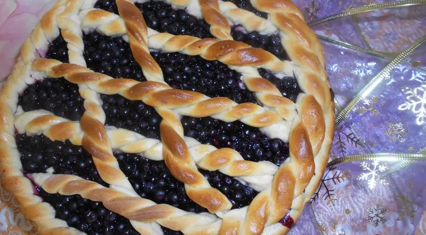 Blåbær med sukker lå ut på deigen, arrangere en kake med pigtails, smør eggeplommen, bake