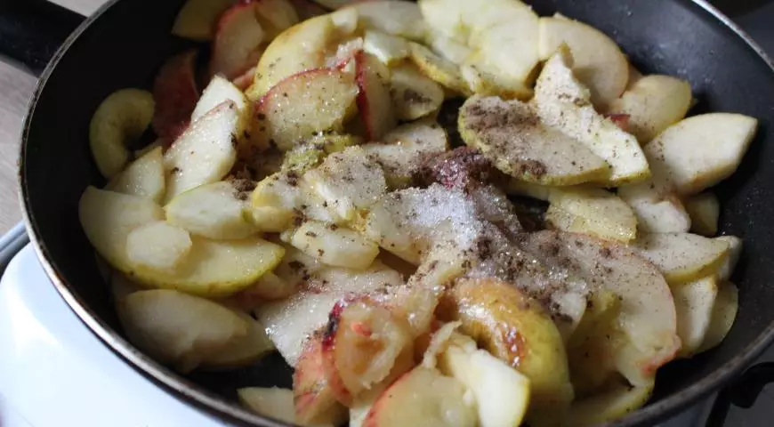 Stänk äpplen med socker och kanel, slaktkropp i en stekpanna i smör