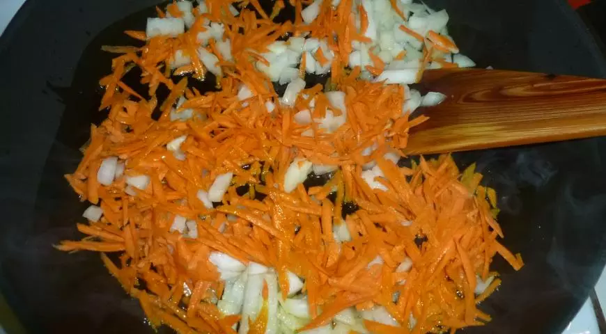 Freír cebollas trituradas y zanahorias para cocinar.