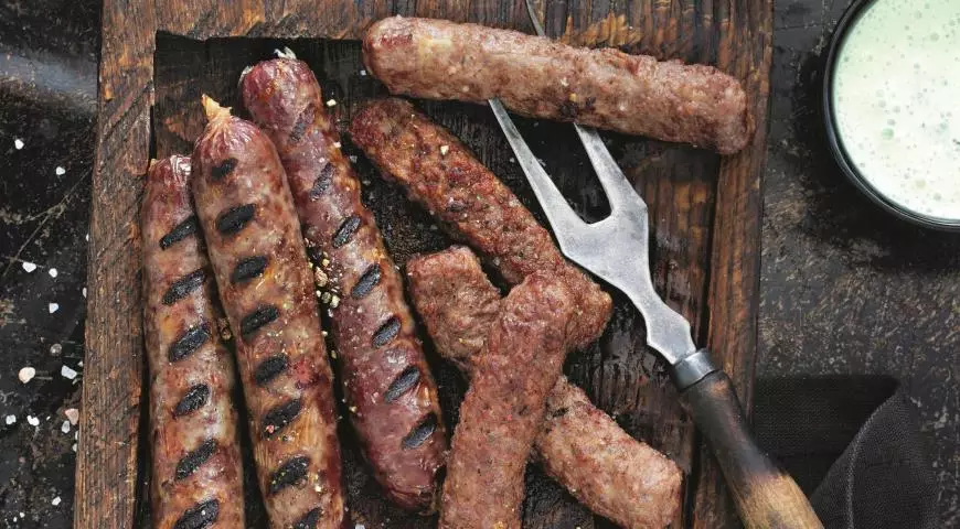 Sausages on coals with three sauces