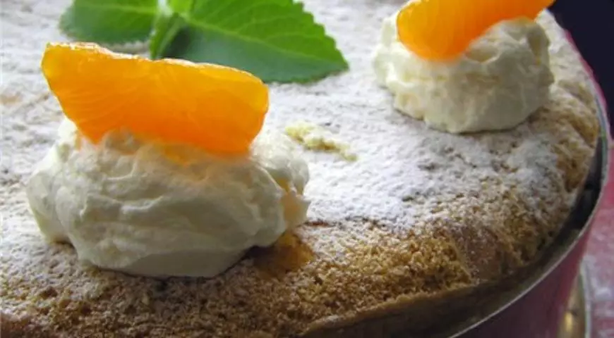 کیک یخ زده با پودر شکر پودر شده و برش های نارنگی را تزئین می کند