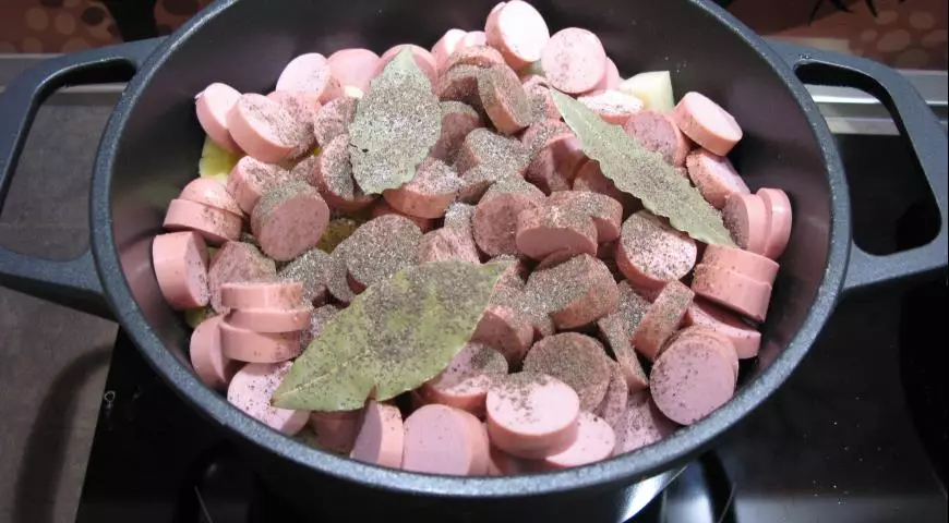 Añadir especias y hojas de laurel a salchichas y verduras.