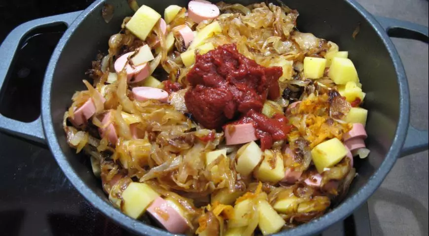 Añadir la pasta de tomate y el agua a las verduras y salchichas.