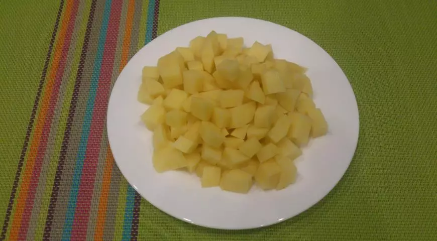 Corte batatas com cubos para cozinhar sopa