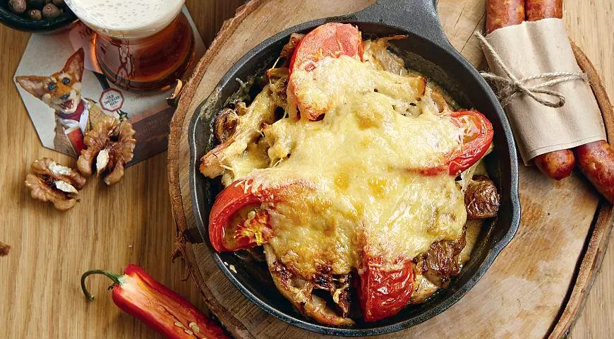 Pollo al horno con tomates y queso, en una sartén.