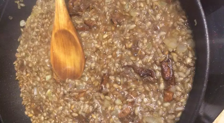 Een risotto van een gerst bereiden met witte paddenstoelen