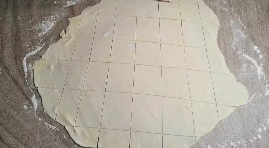 Tabulka posypeme moukou, válcování těsta do tenkého plechu a nakrájejte na kostky