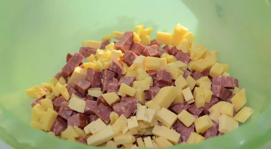 Matlagning pasta och skära korv och ost