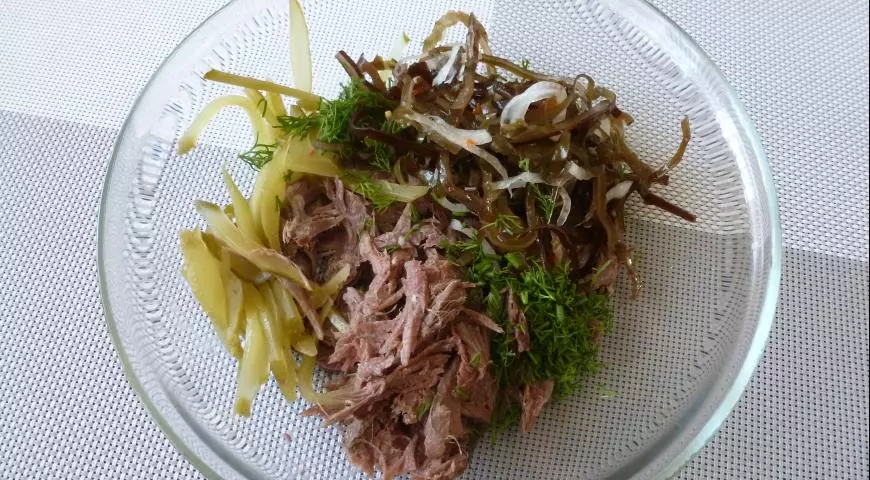 Mezclamos la carne hervida con algas y pepino salado.