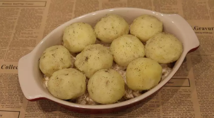 Von Kartoffelpüree-Kartoffeln rollen Kugeln und legen sie auf Fleisch unter Sauce