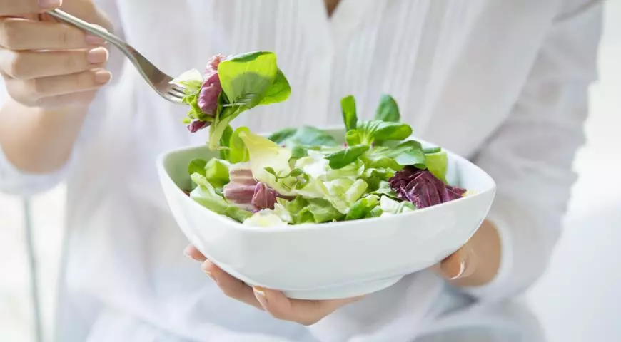 A rapaza come ensalada de luz