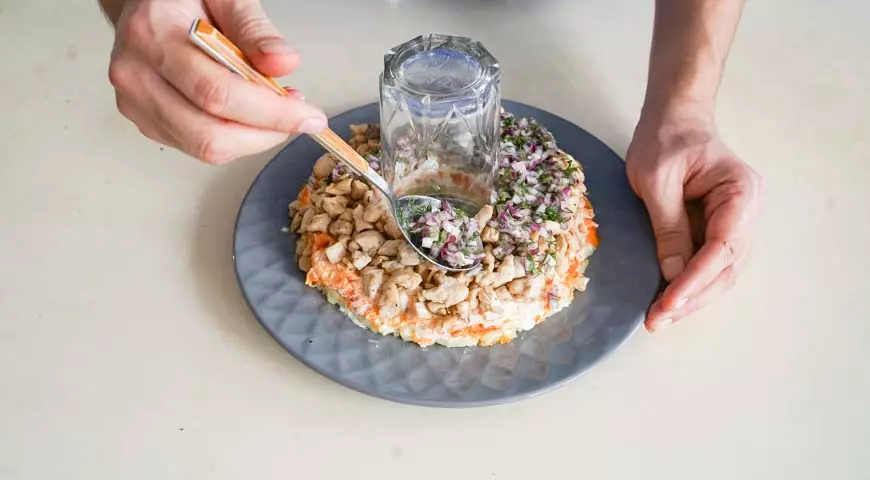 Pulsera de granada de ensalada con pollo, la tercera capa - pollo, cebollas y eneldo, frotis por mayonesa