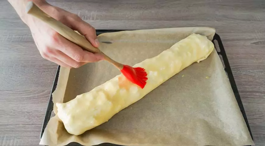 Strudel vienés con manzanas, manchando el rollo con mantequilla.