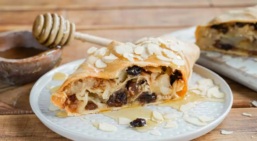 Strudel vienés con manzanas, corte el rollo acabado en la porción, espolvoree por la miga de almendras