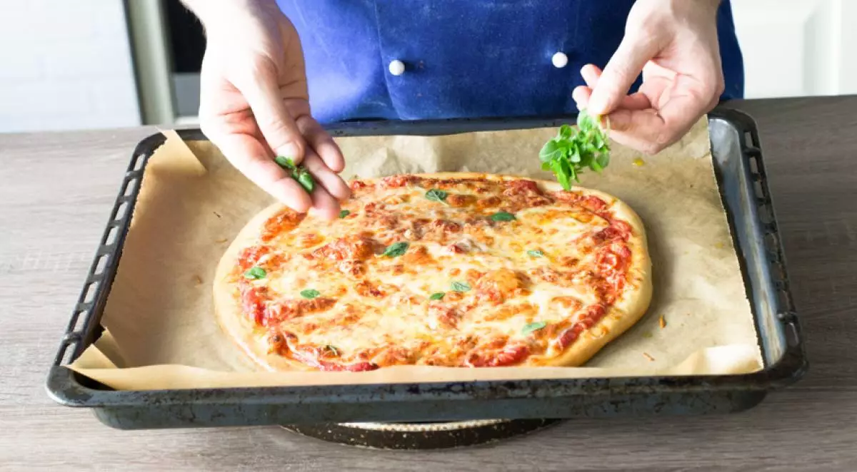 Pizza delgada, decore una pizza de albahaca.