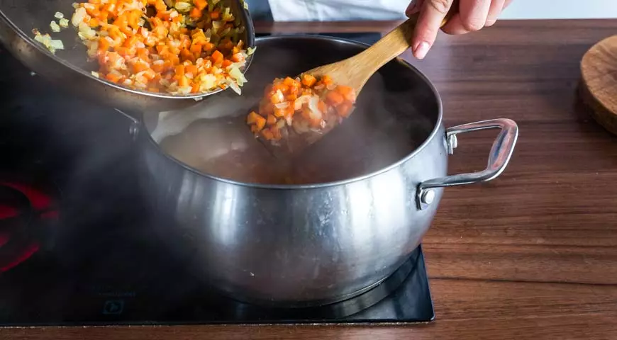 Sopa ahumada de guisantes, agregar zanahorias y cebollas en sopa.